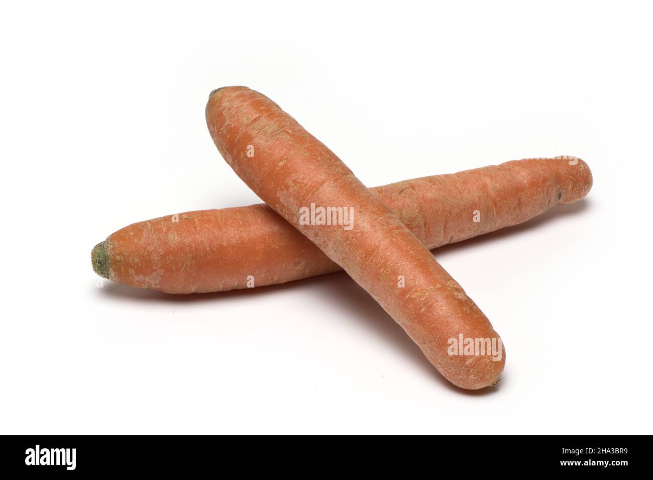 two ripe orange carrots crossed lying on each other isolated on white ...