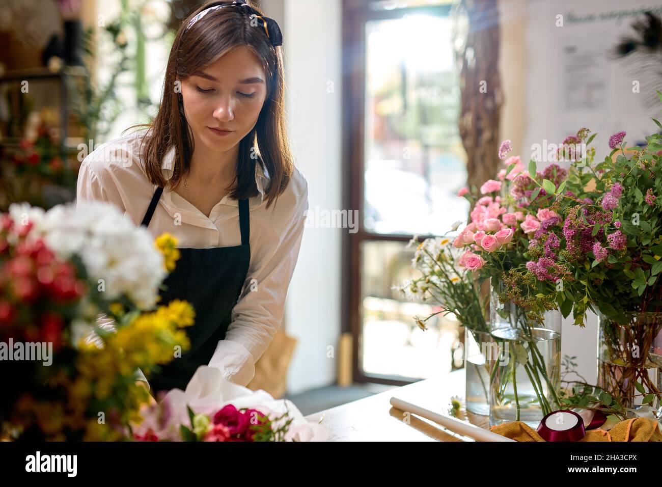 Florist at work: pretty european woman arranging floral decorations ...