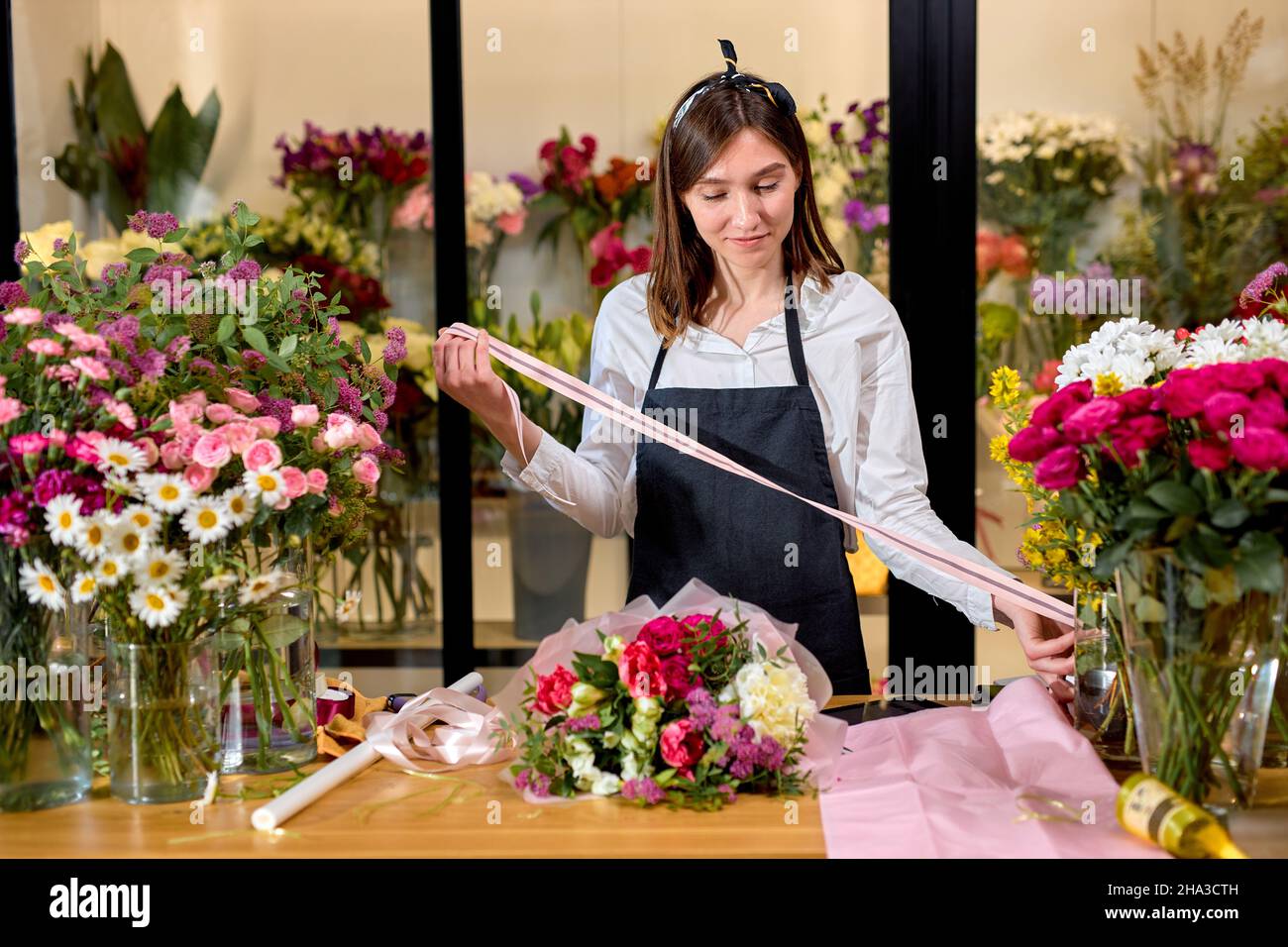 Florist at work: pretty caucasian woman arranging floral decorations ...