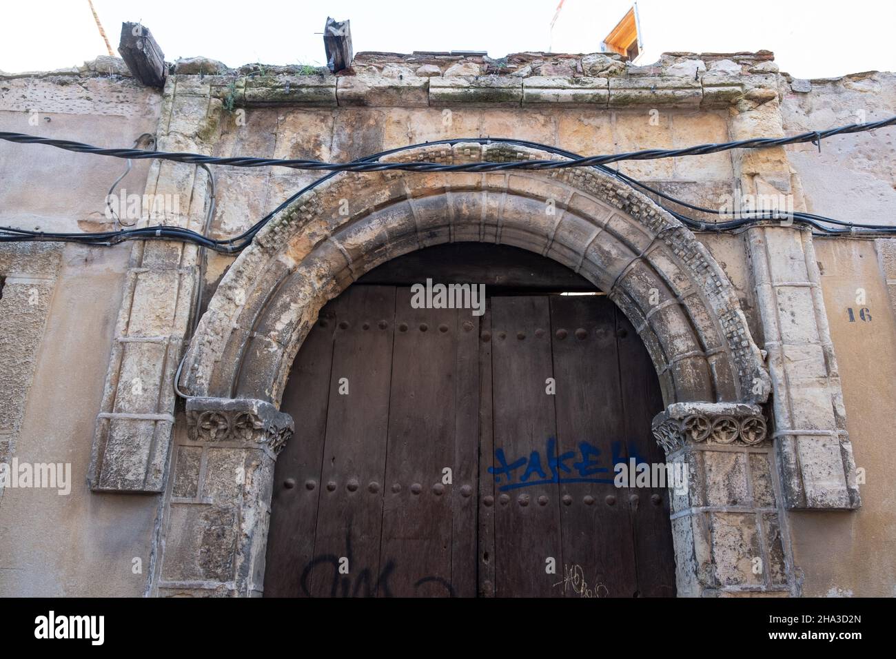 Cables cross an ancient Romanesque façade. Deterioration and ruin of ...