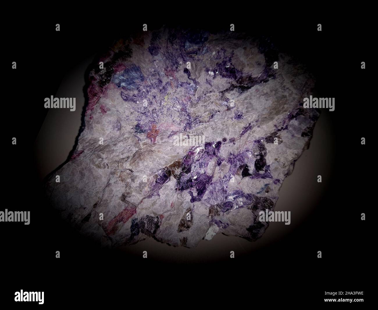 Close-up on a pegmatite rock, with vibrant colors in dark pink tones ...