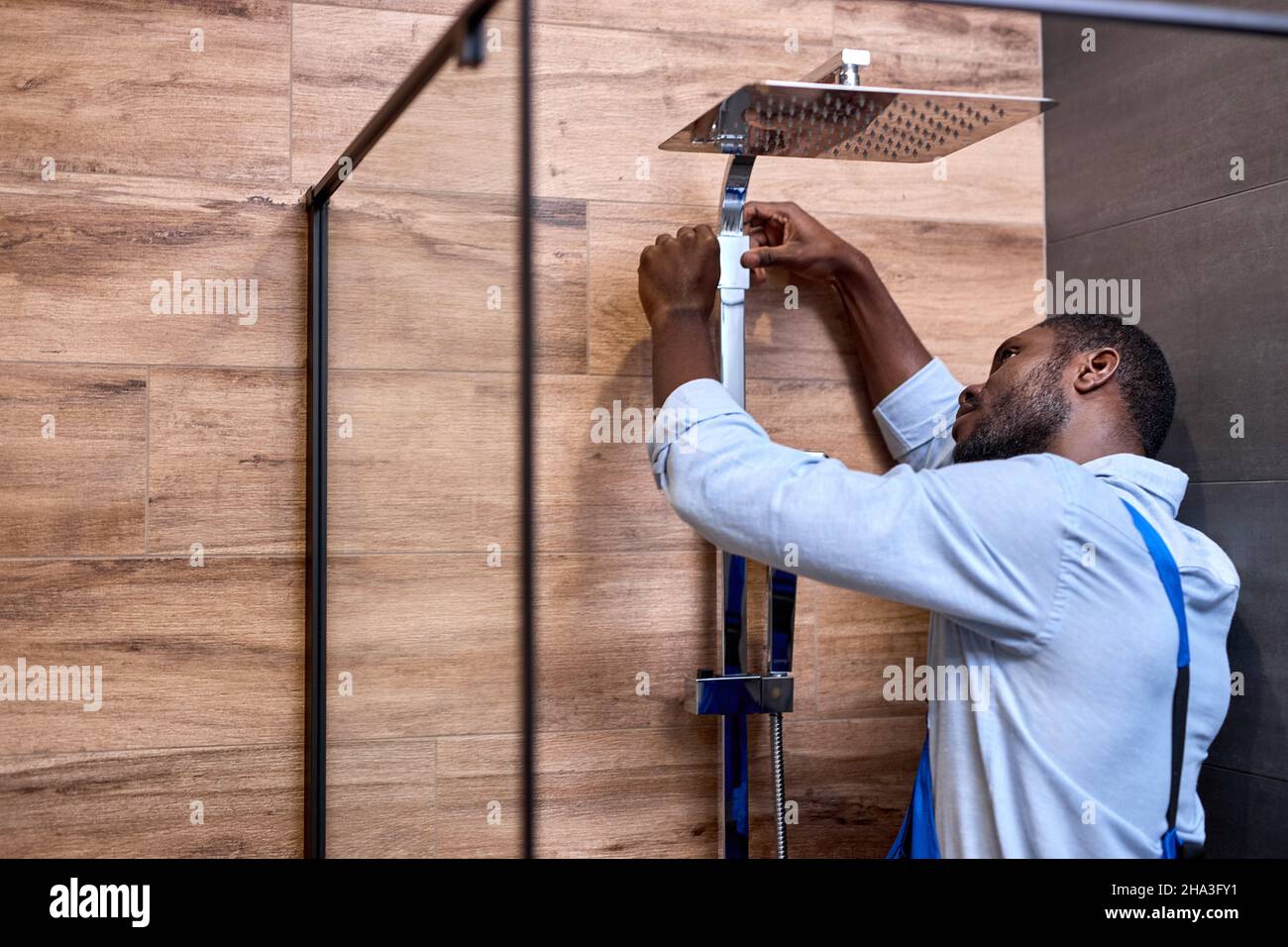 African Professional handyman working in shower bath indoors, side view ...