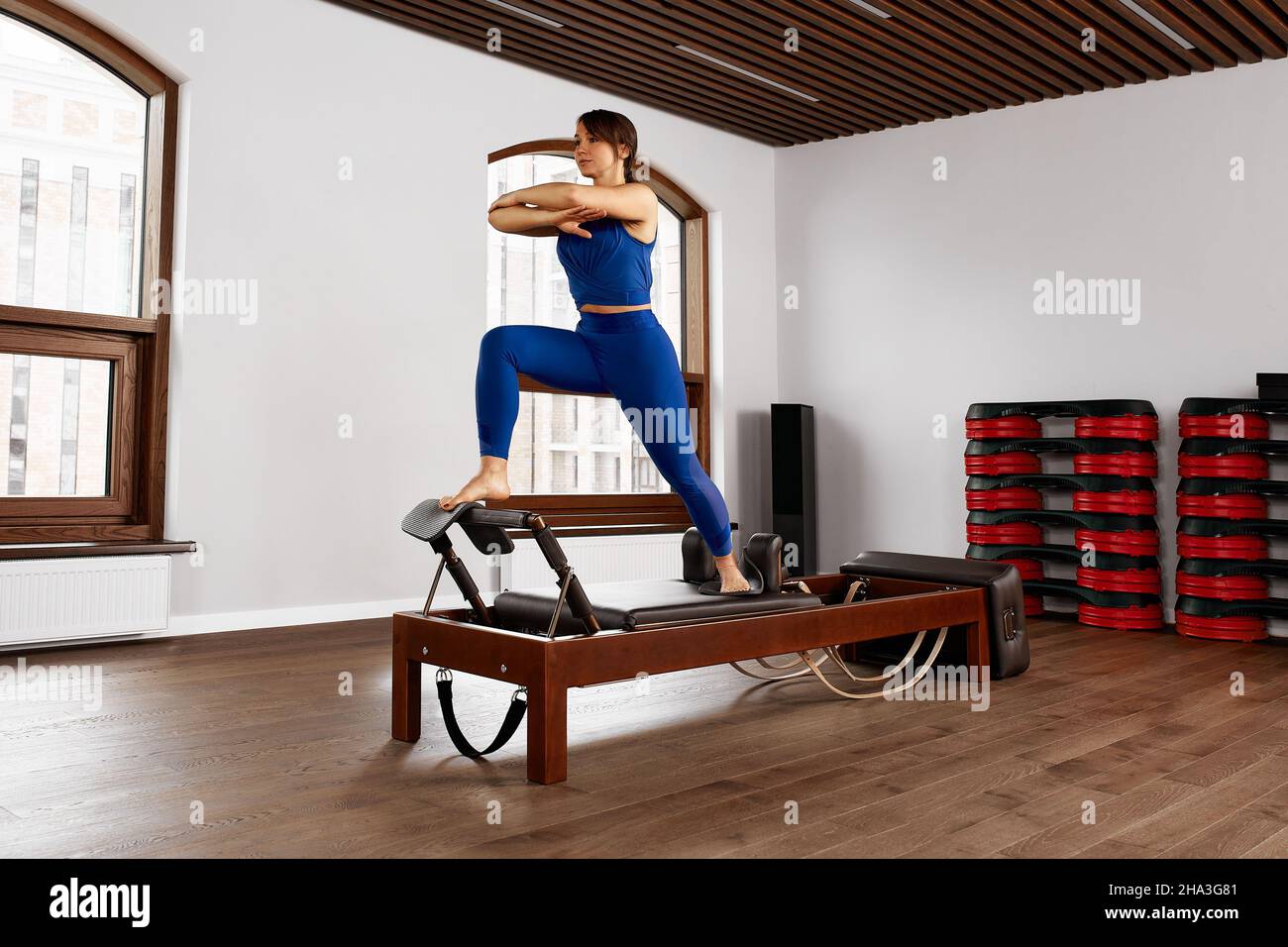 The instructor does exercises on the reformer, a beautiful girl trains ...