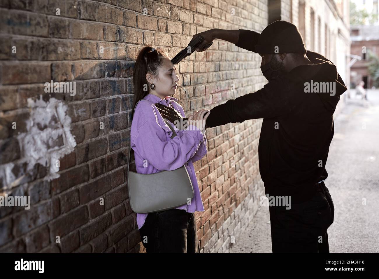 Dangerous criminal in black casual wear and mask is gun-threatening ...