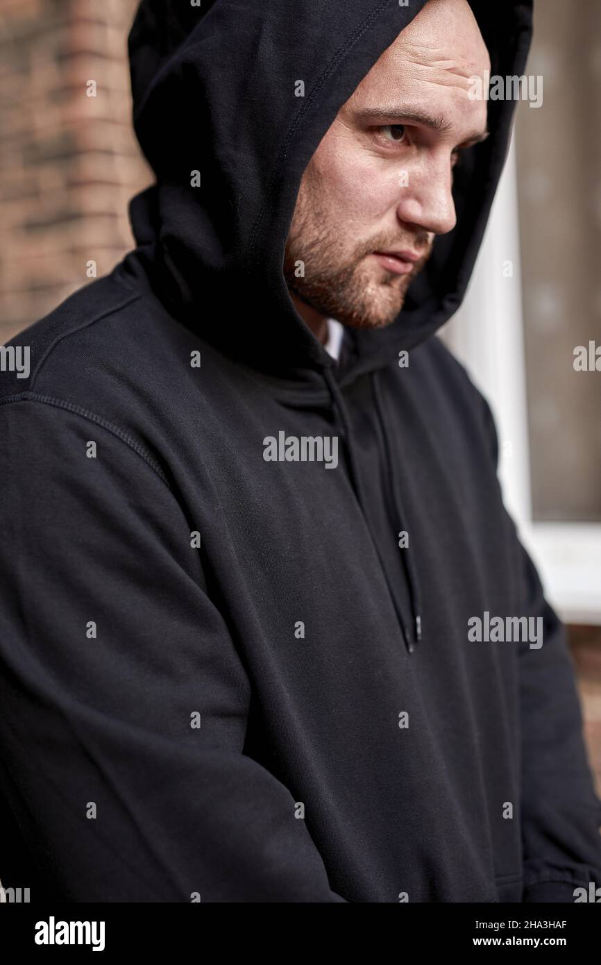 Dangerous caucasian bearded man in the hood, in black wear, confident ...