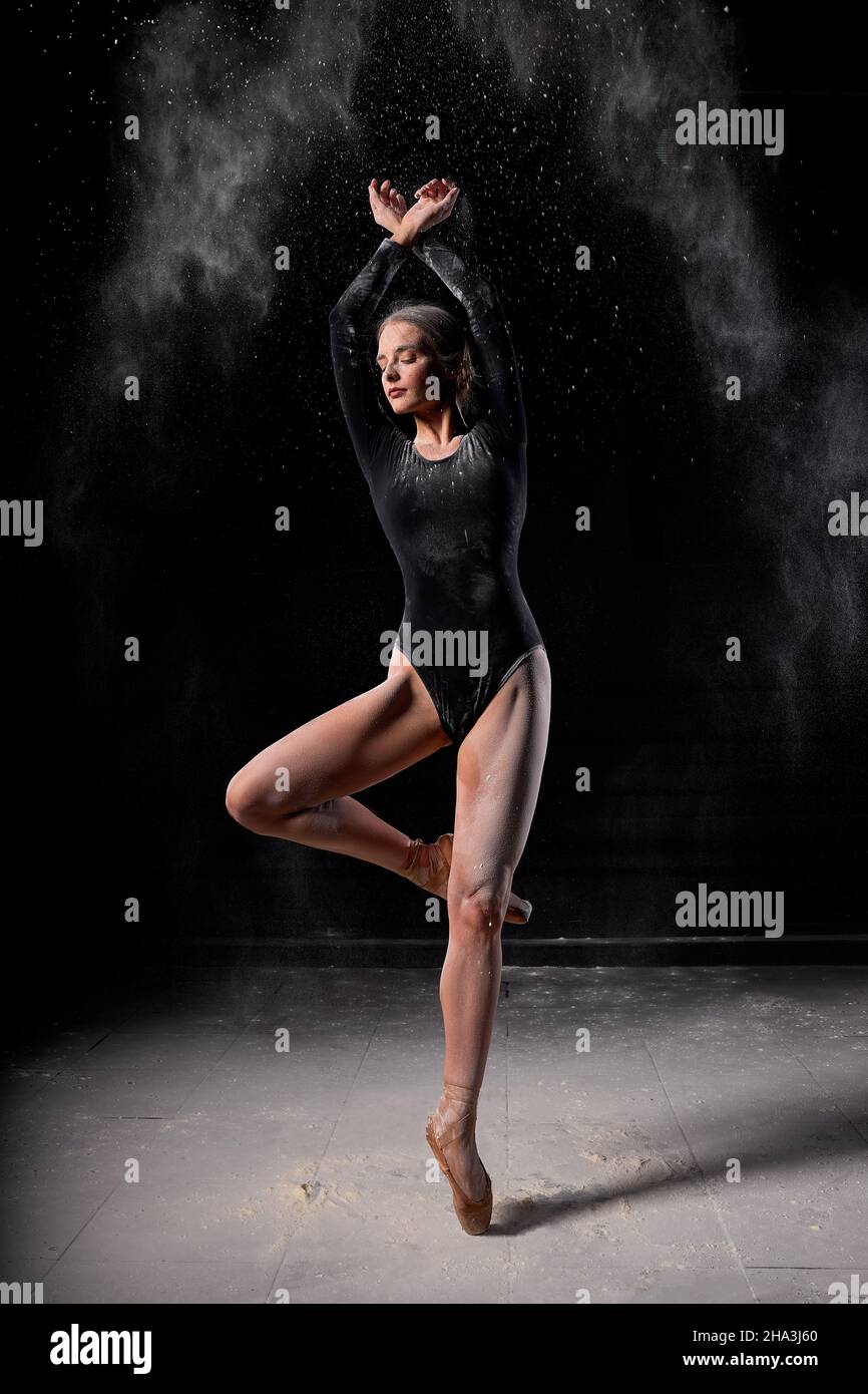 Dancer posing dancing gracefully in studio with cloud of dust, flour ...