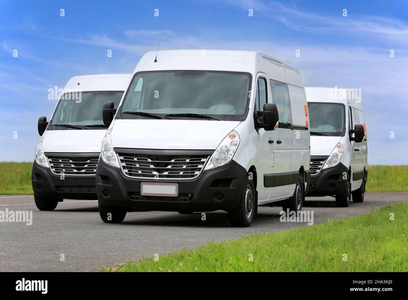 Three white delivery vans parked on a yard, ready to transport goods ...