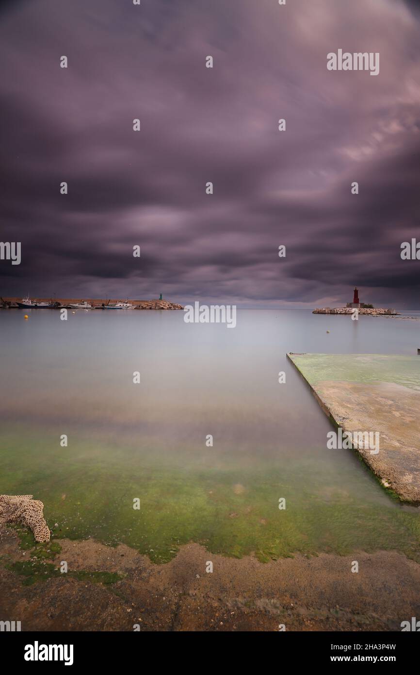 View of a lighthouse on the calm sea under the cloudy sky Stock Photo ...