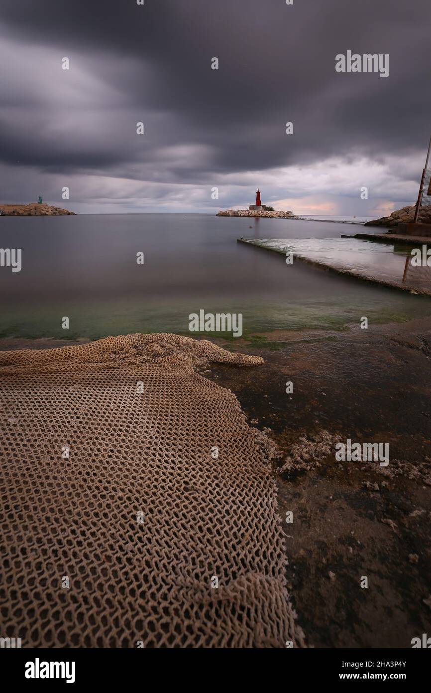 View of a lighthouse on the calm sea under the cloudy sky Stock Photo ...