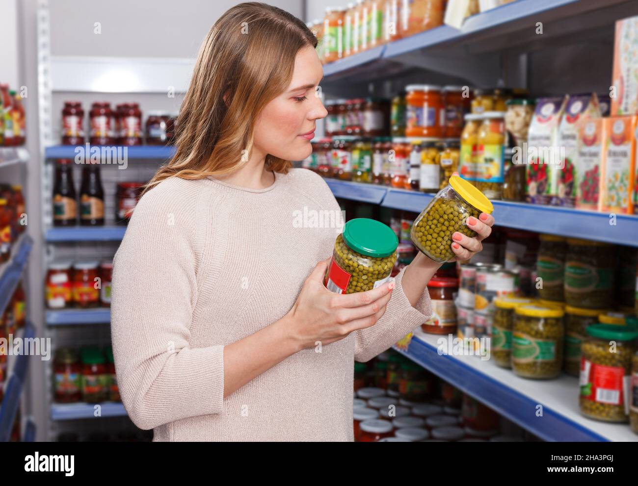 Positive female customer choosing pickle goods in store Stock Photo - Alamy