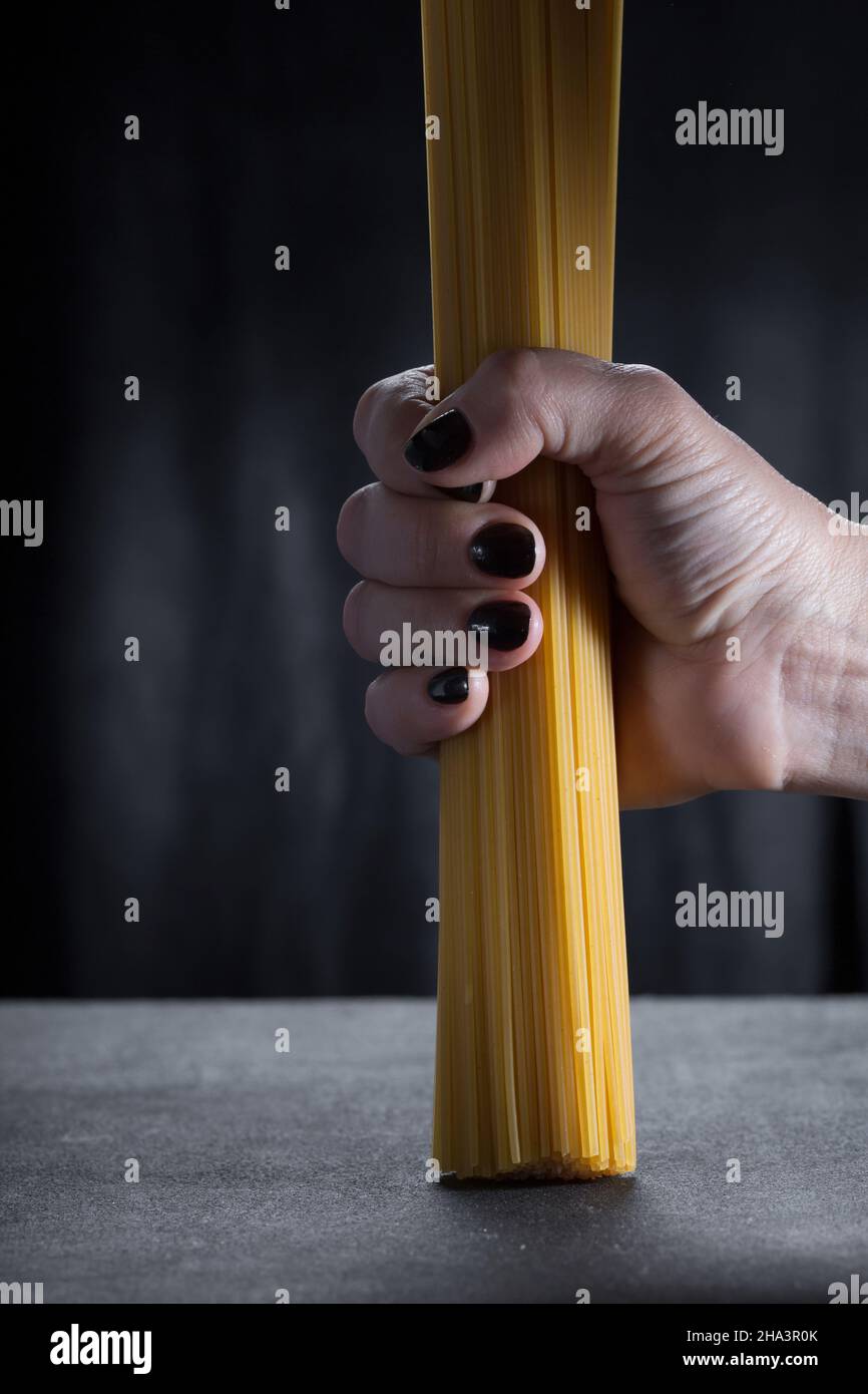 Minimalistic image of spaghetti pasta in hand close-up Stock Photo - Alamy