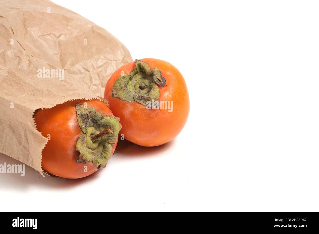Persimmon fruit in a grocery paper bag on a white background Stock ...