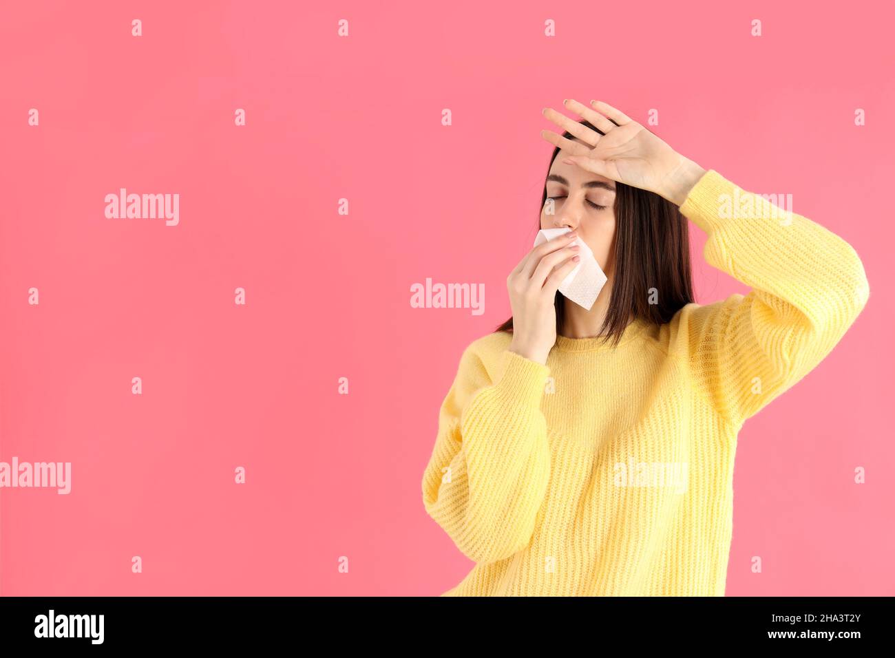 Sick girl in a yellow sweater on a pink background Stock Photo - Alamy