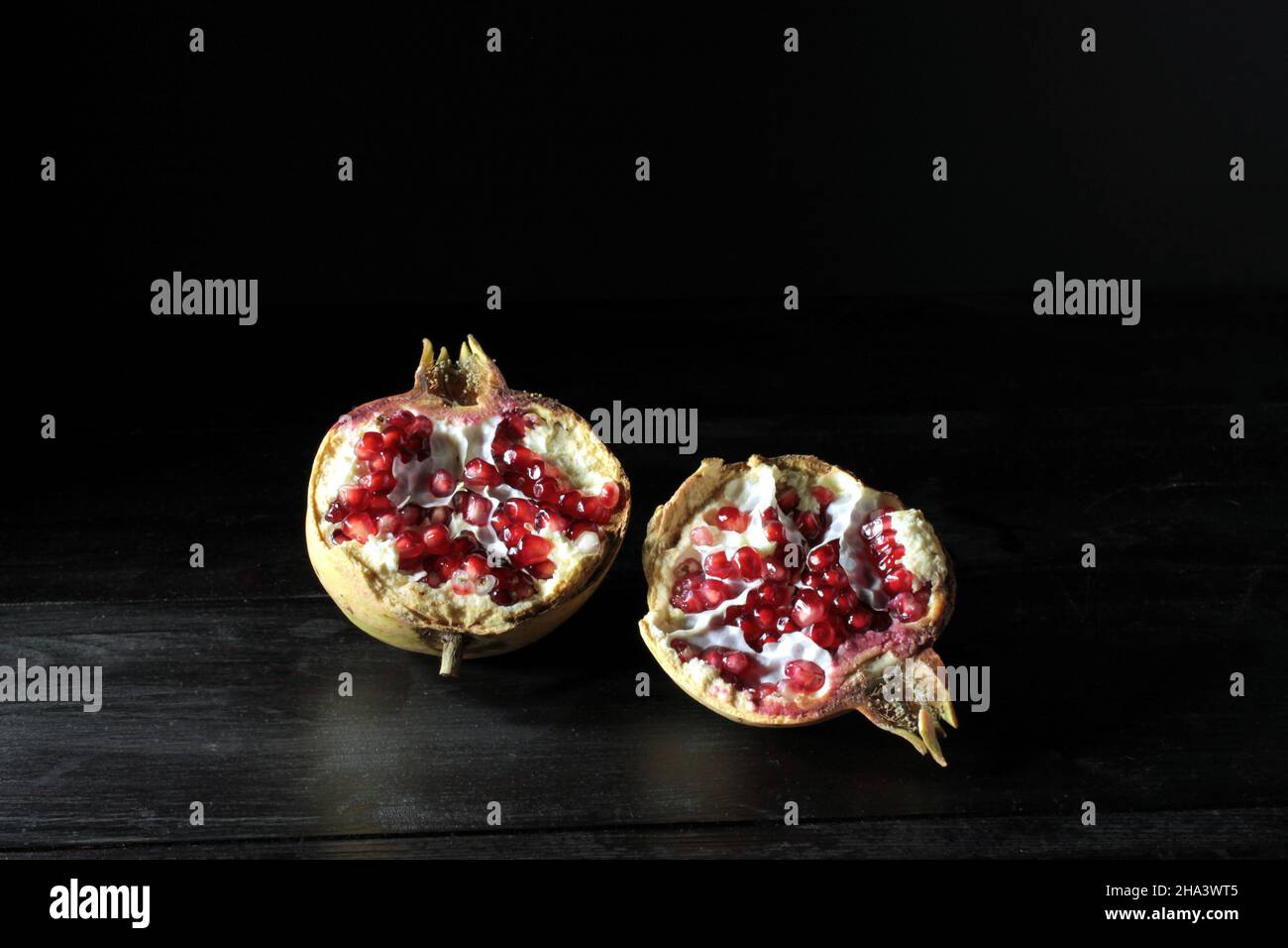 Pomegranate split in half on dark wood table and black background Stock ...