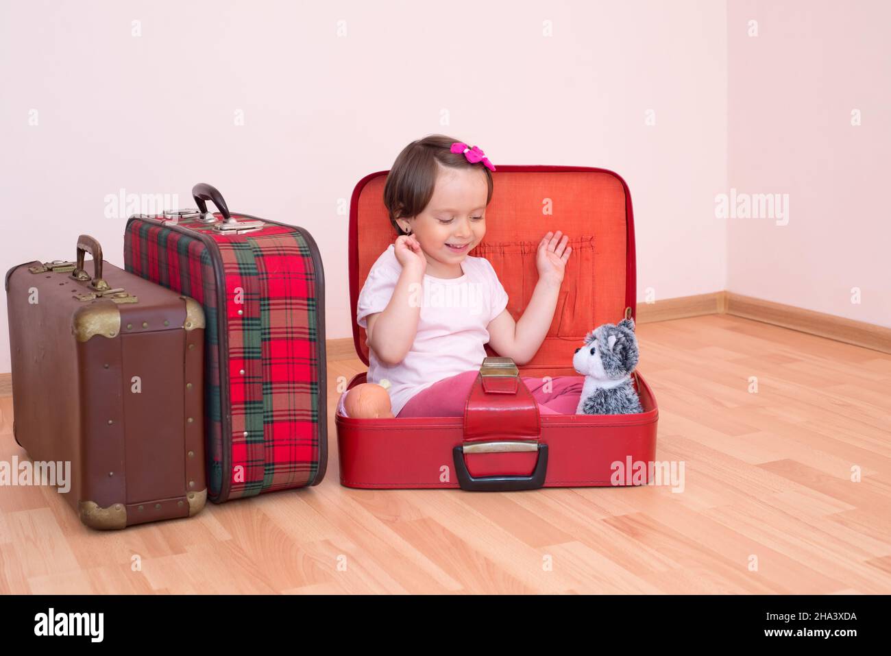 Little girl sitting in a suitcase and playing with her toys Stock Photo ...