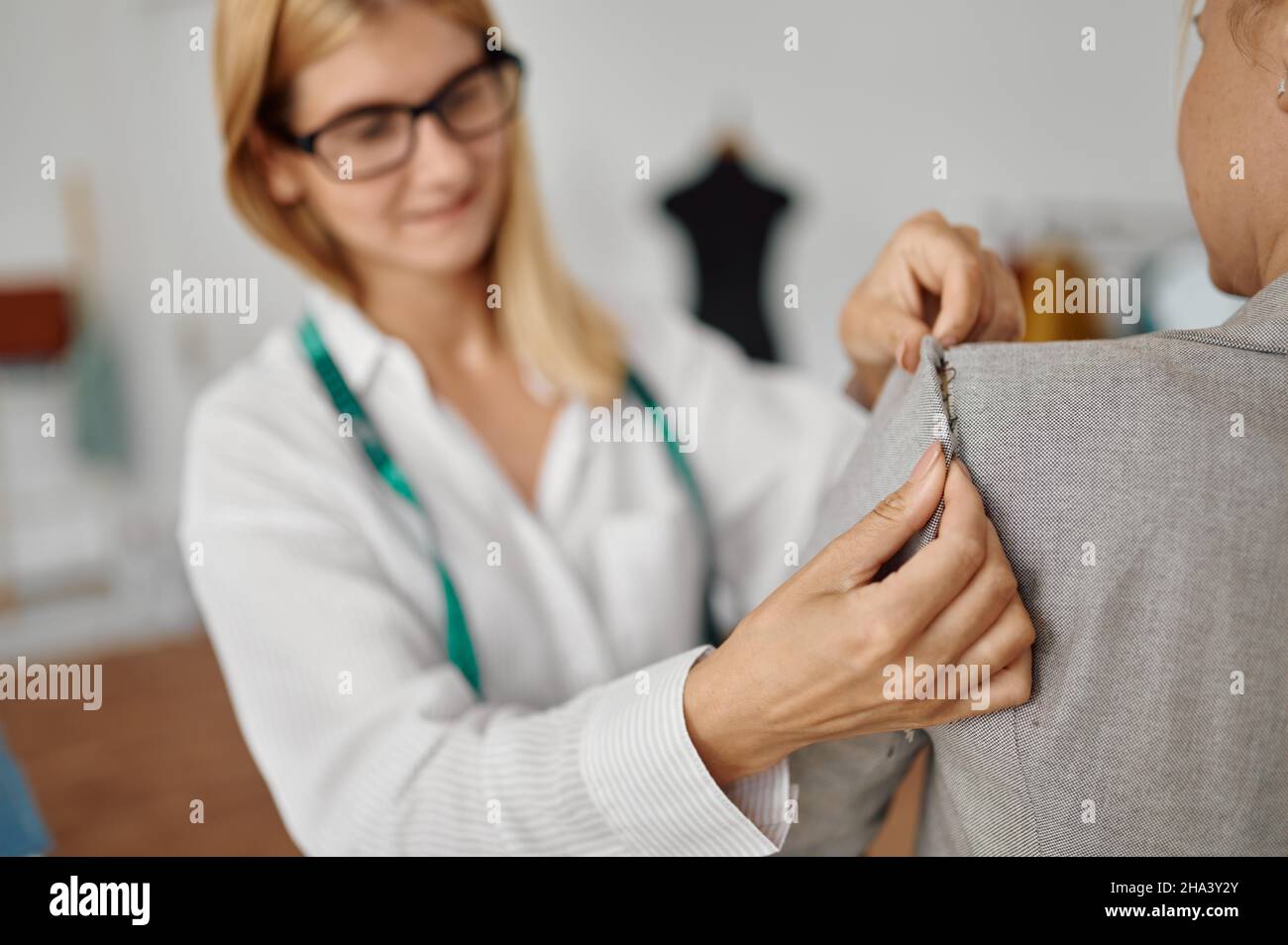 Seamstress takes measurements from woman, workshop Stock Photo - Alamy