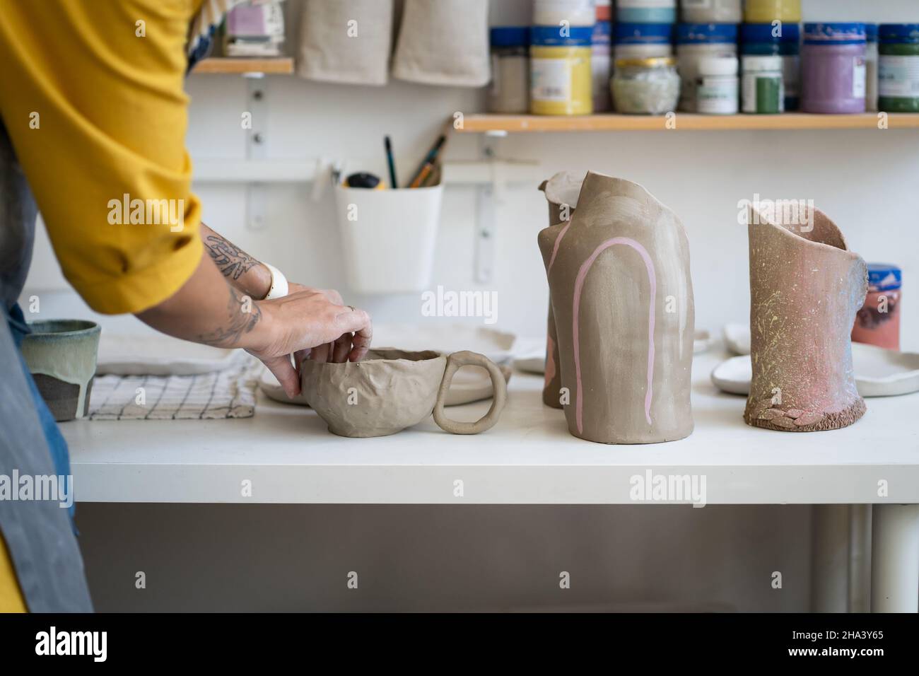 Workplace of craft ceramist with handmade ceramics. Female artist shape ...