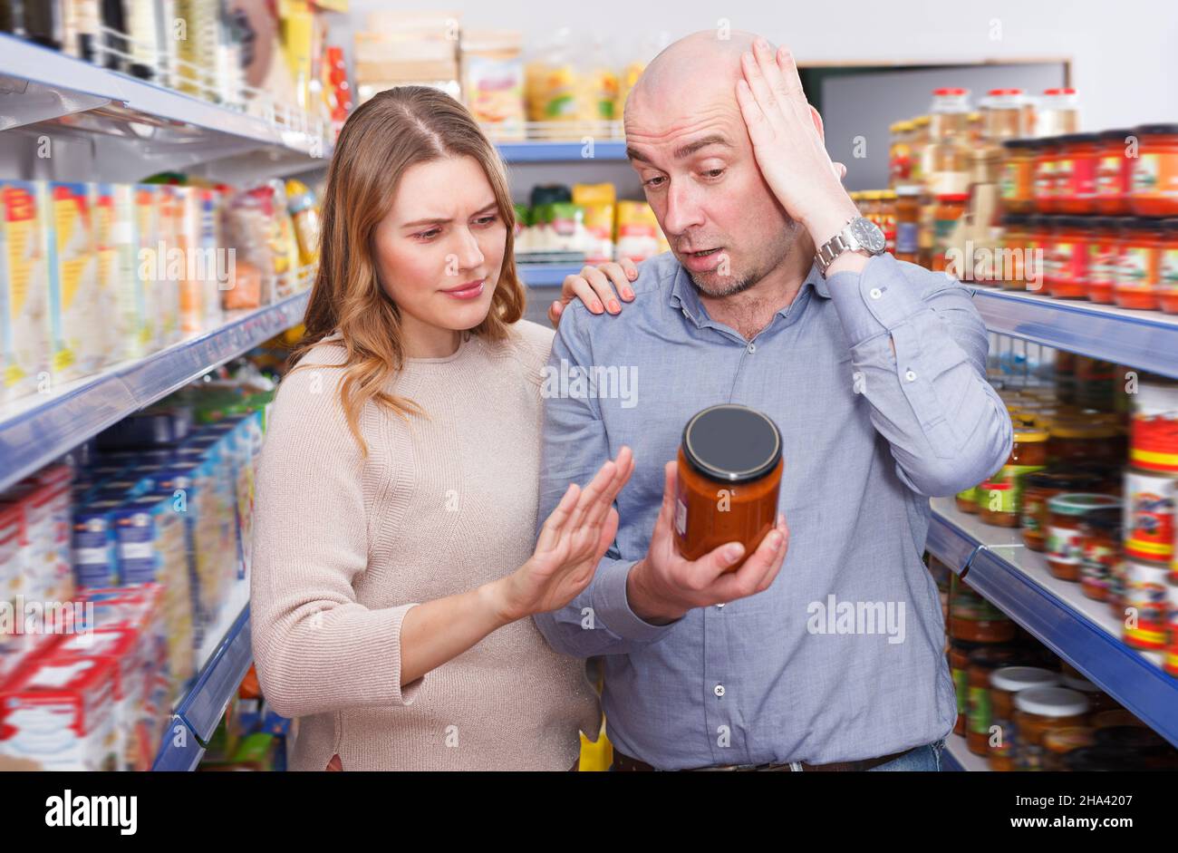 Nice couple in the store holding preserved goods in grocery section ...
