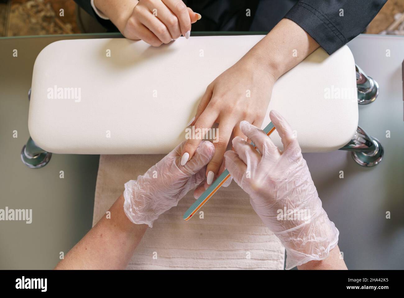 Close-up of woman in nail salon doing manicure by beautician with nail ...