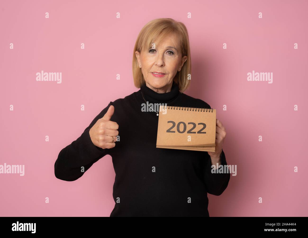 Senior woman showing calendar with thumb up standing isolated over pink ...