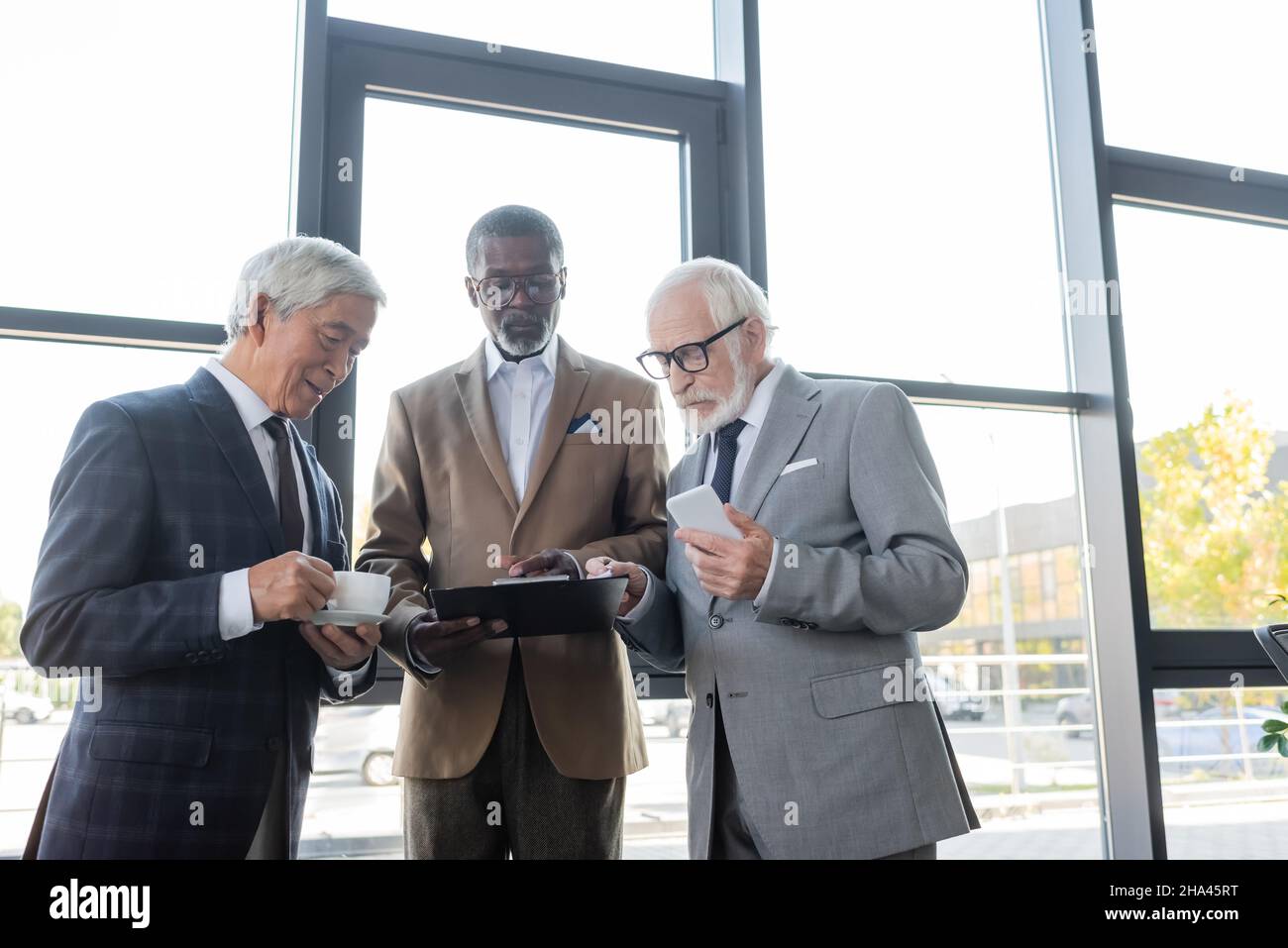 senior multiethnic business partners discussing contract in office ...