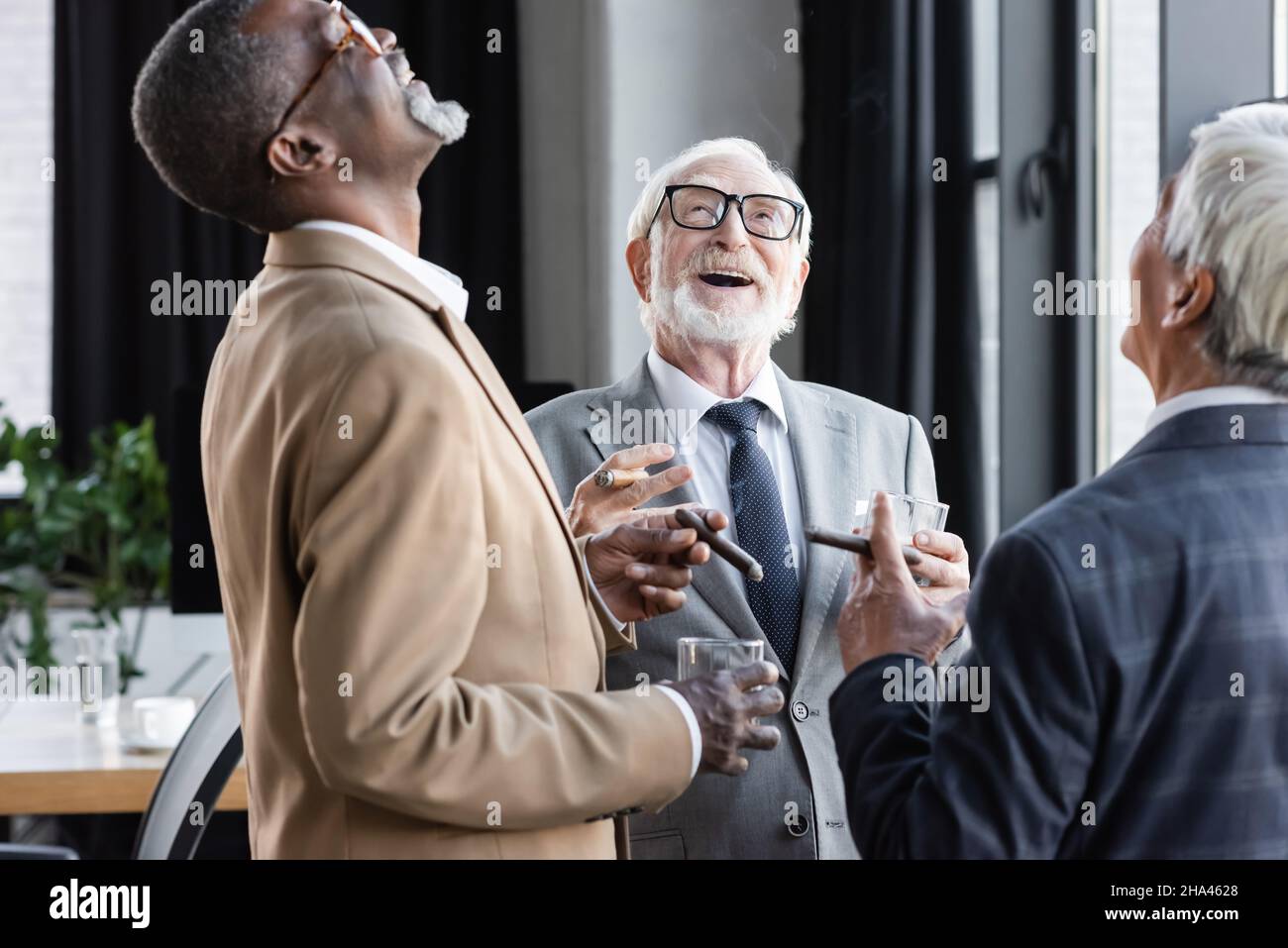senior multiethnic businessmen laughing while drinking whiskey and ...