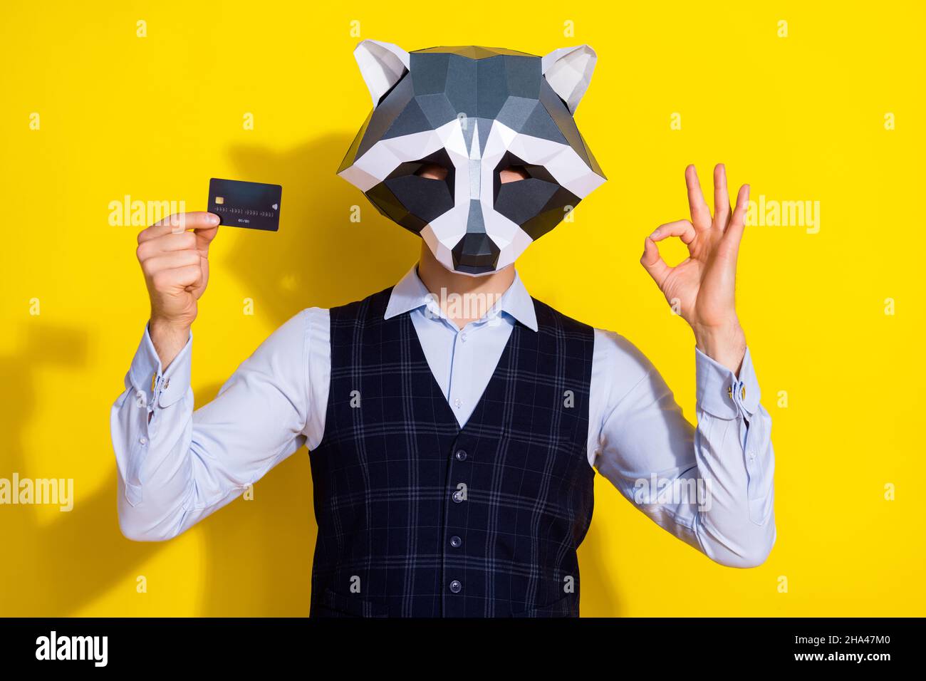Photo of weird anonym banker guy racoon mask hold debit card ...