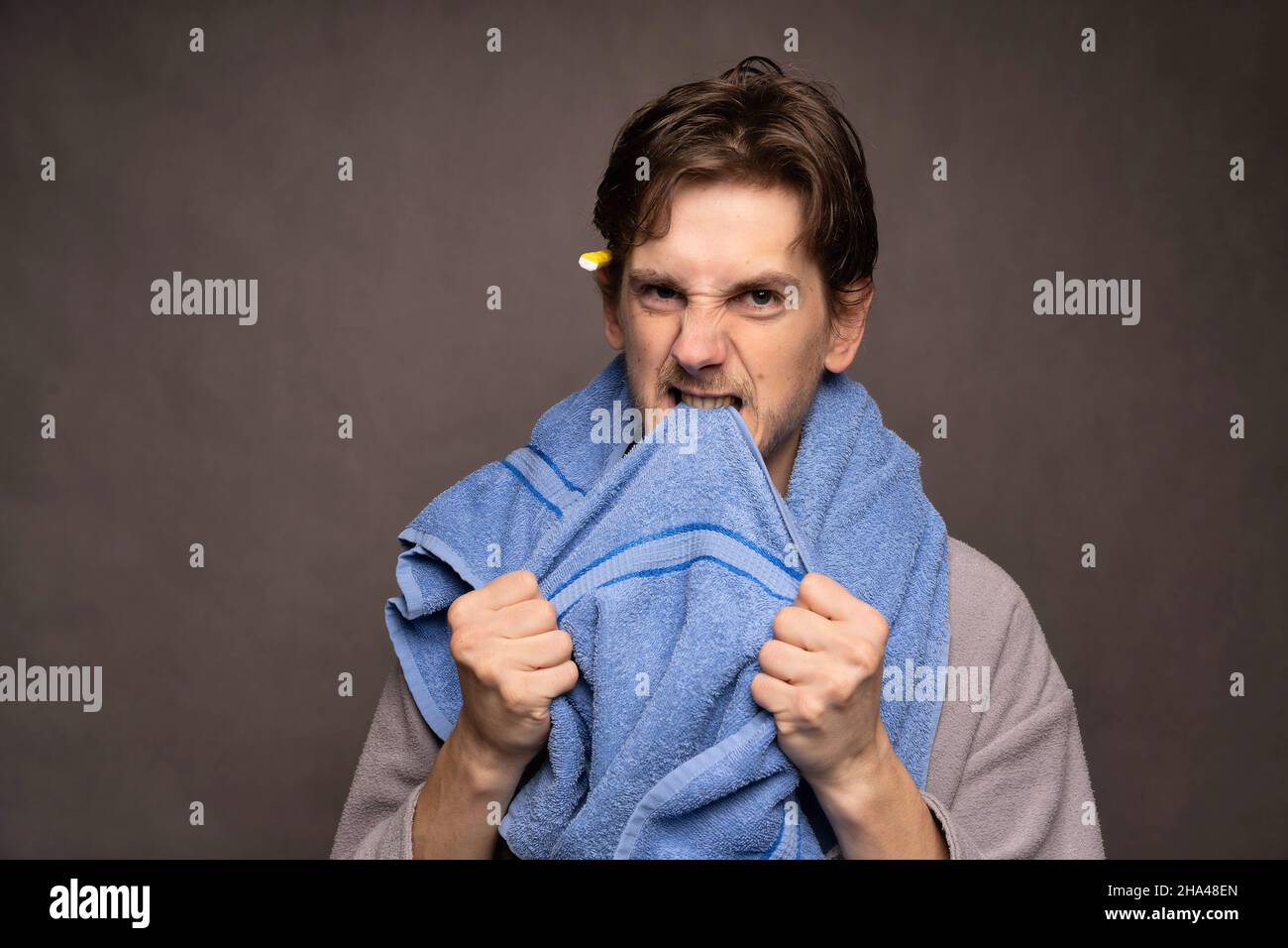 Young handsome tall slim white man with brown hair angrily biting into ...