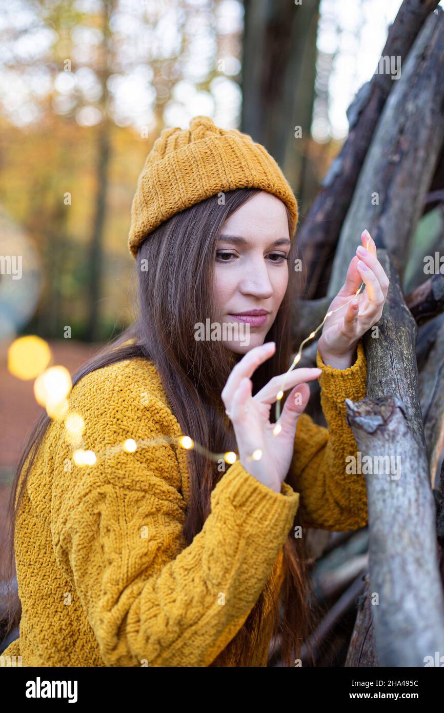 White young woman in warm yellow pullover portrait with lights in front ...