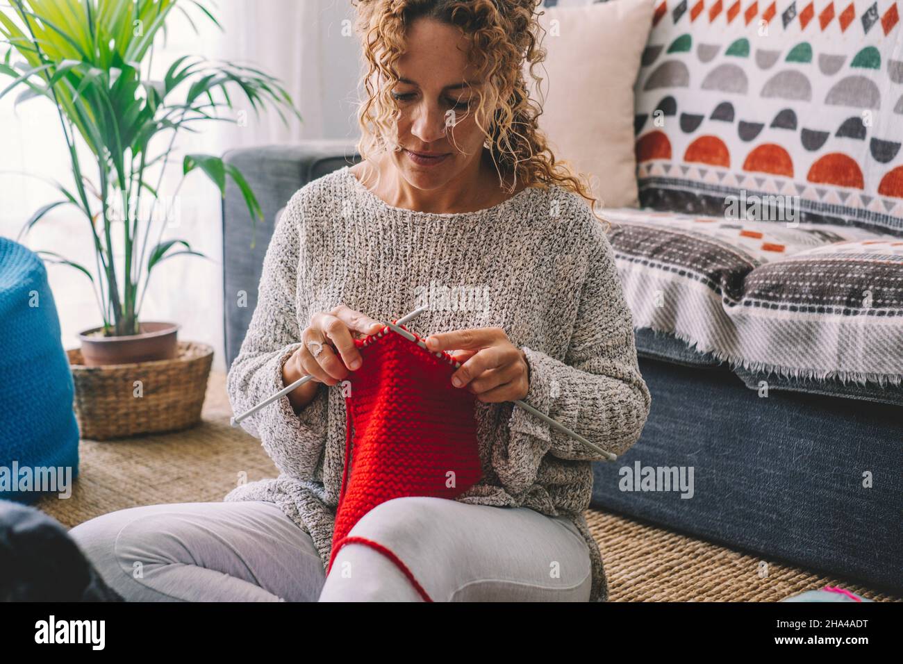 happy pretty woman smile and admire her knit work wit red colorful wool ...