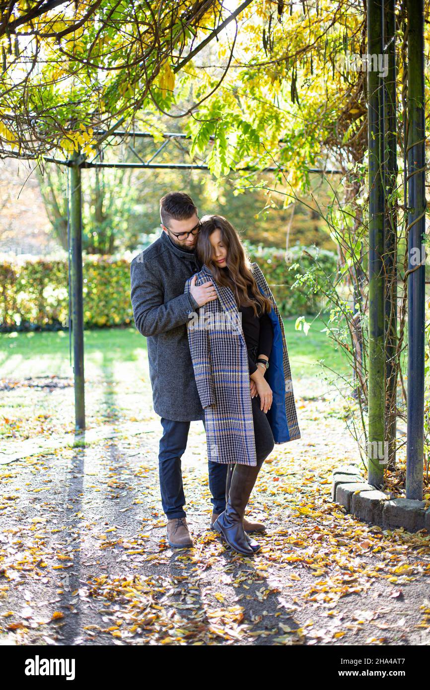 Romantic embracing young european man and woman with dark hair in park ...