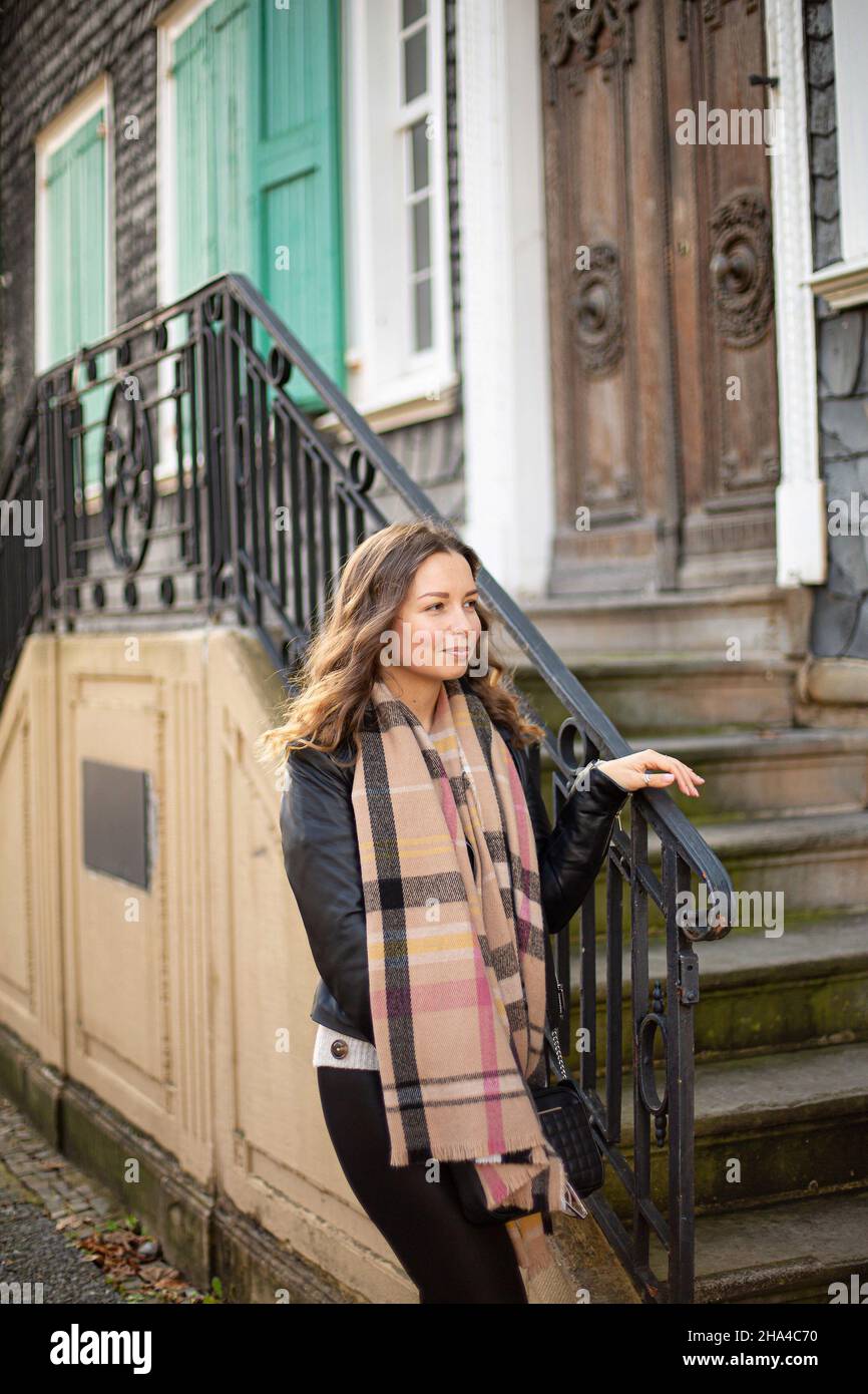 Smiling white young european woman with brown hair with stairs behind ...