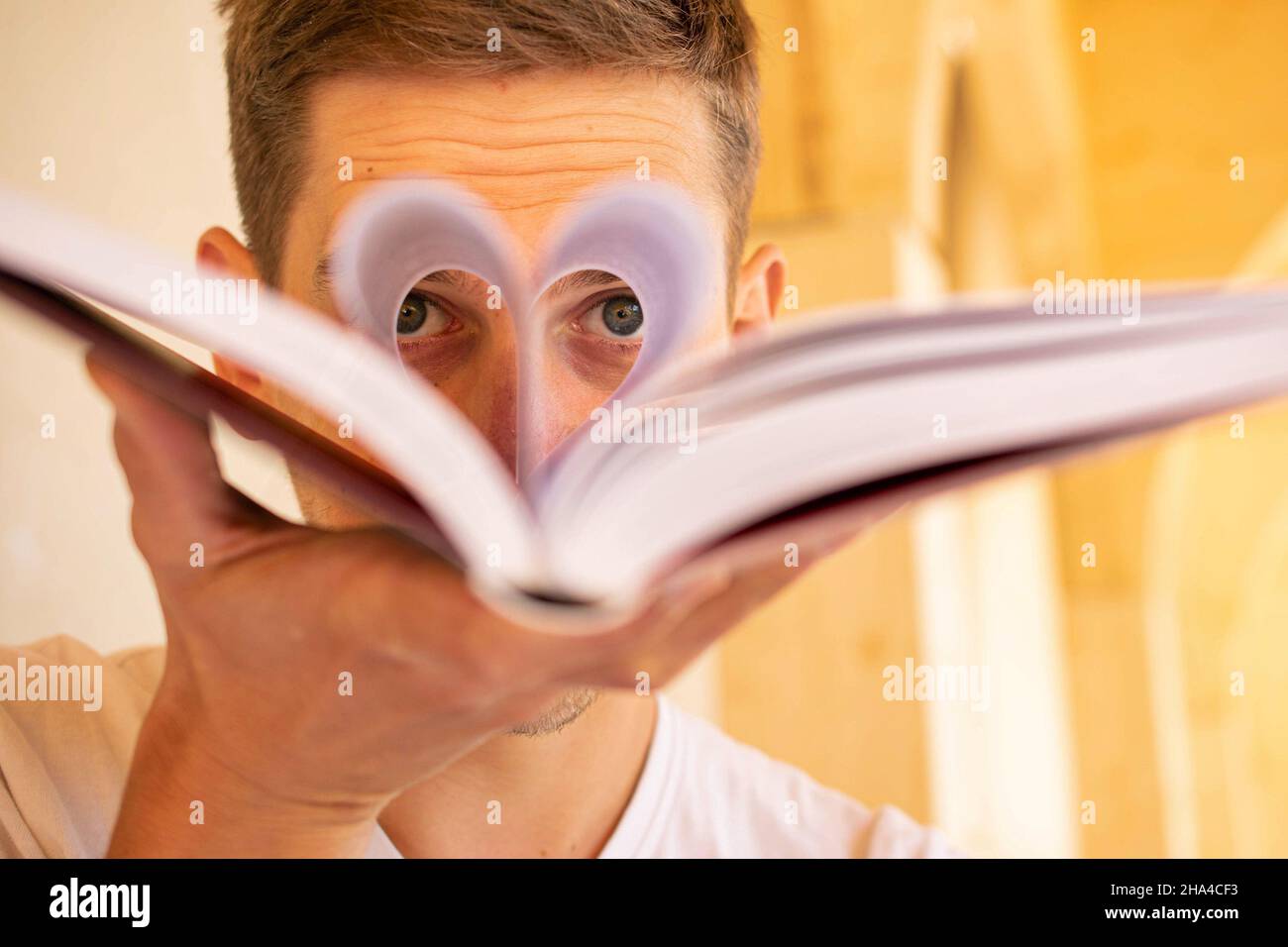 Young handsome white man with brown hair is looking through book pages ...