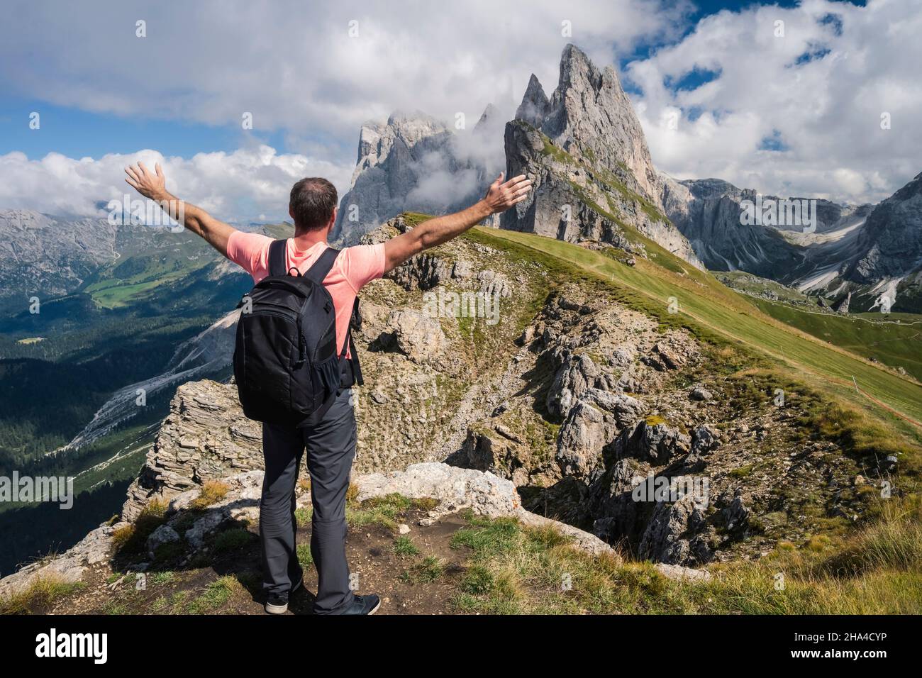 a man with backpack raised his hands enjoying landscape of seceda peak ...