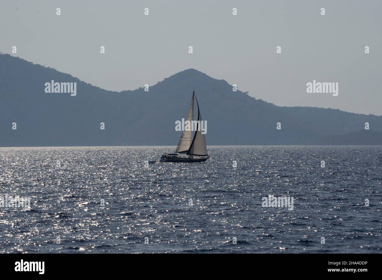 White boat sailing close to the coast blue aegean sea in Greece Stock ...