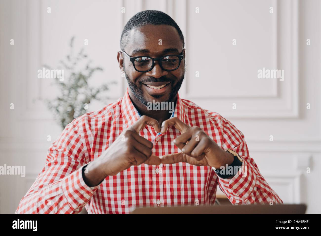 Happy african man gesturing heart symbol shape with hands during video ...