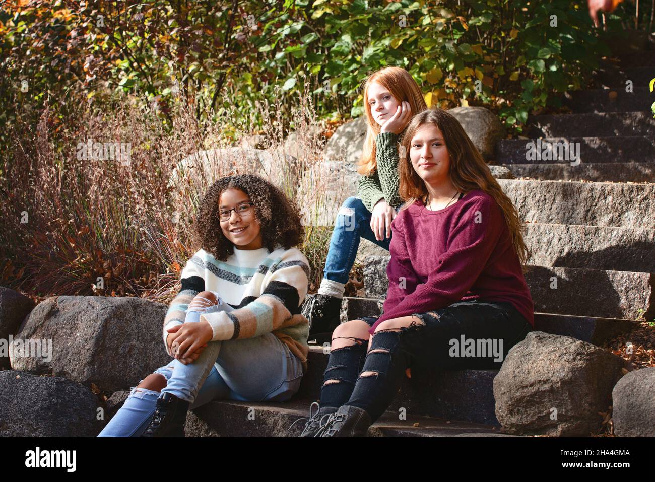 Three pretty tween girls sitting outdoors together Stock Photo - Alamy