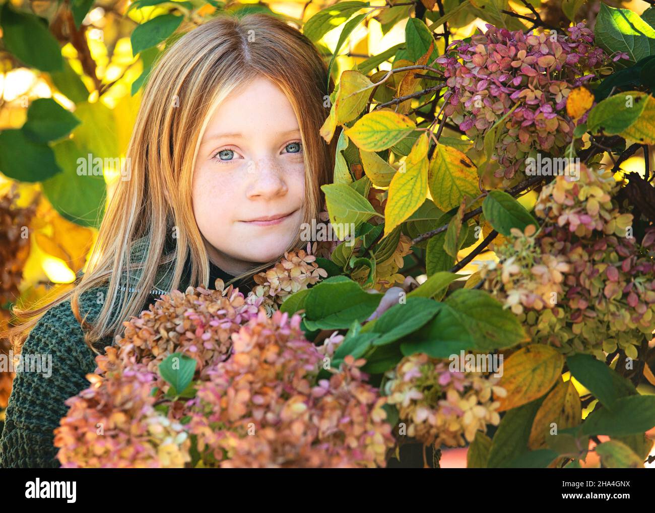 Pretty tween girl with red hair by flowering tree Stock Photo - Alamy