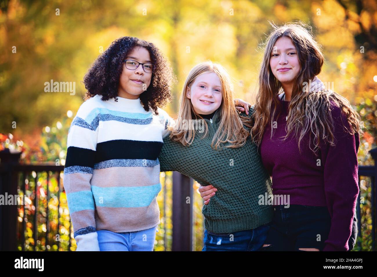 Three pretty tween girls laughing together outdoors in fall colors ...