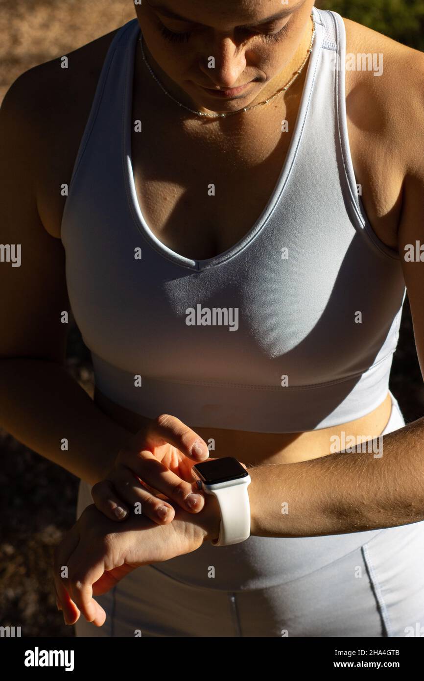 Vertical shot of young Caucasian athletic girl looking at the stopwatch ...