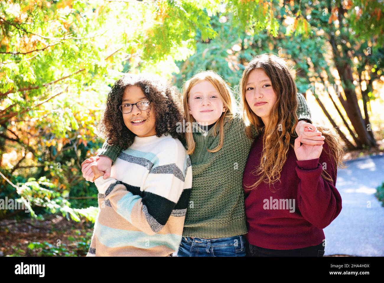 Three pretty tween girls laughing together outdoors in fall colors ...