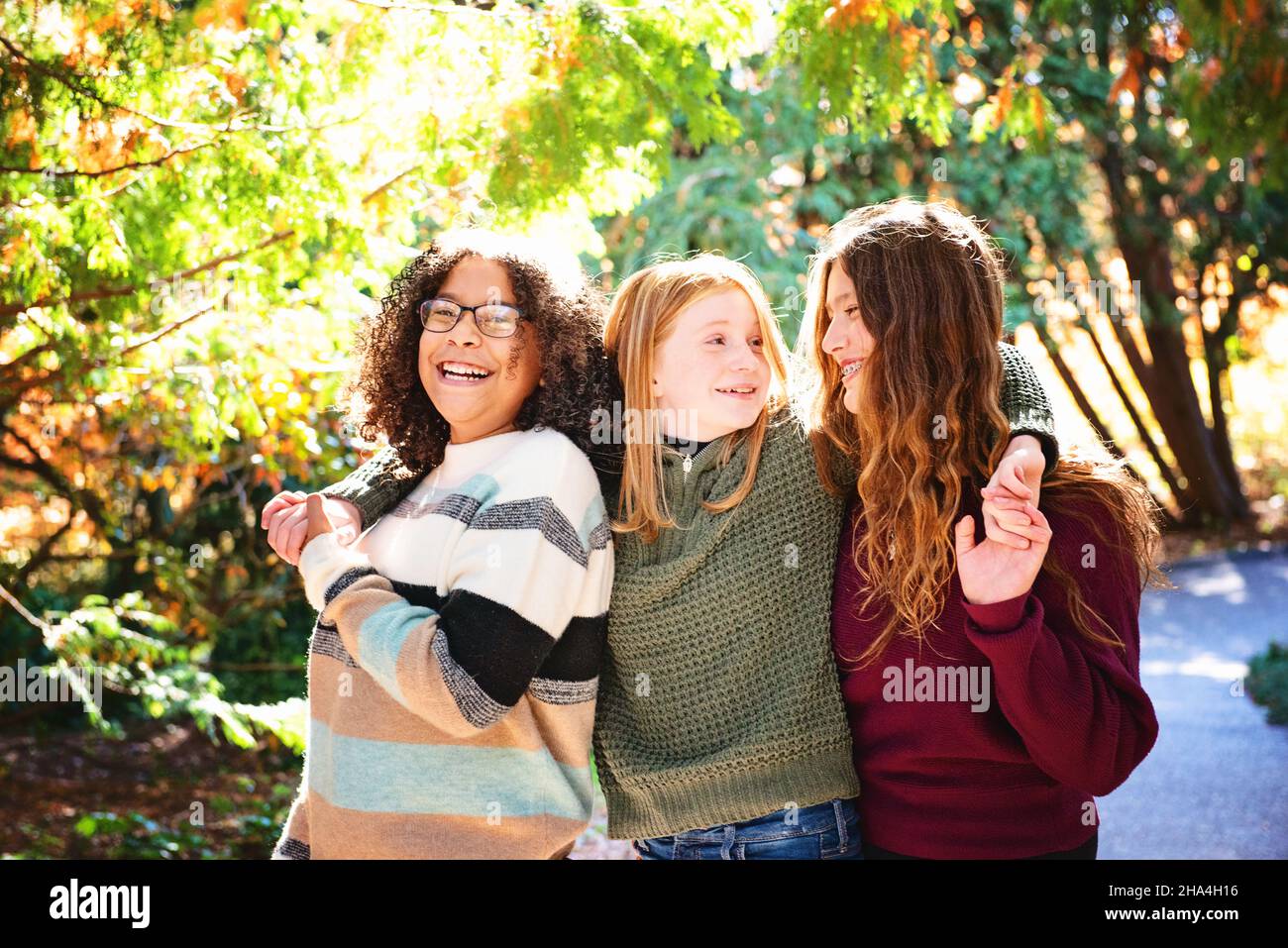 Three pretty tween girls laughing together outdoors in fall colors ...