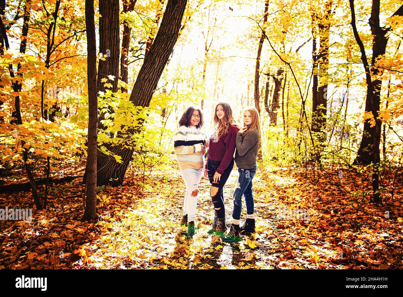 Three pretty tween girls laughing together outdoors in fall colors ...