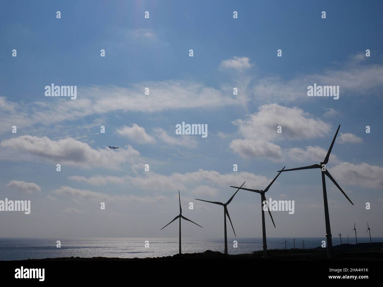 Airplane flying over wind turbines Stock Photo - Alamy