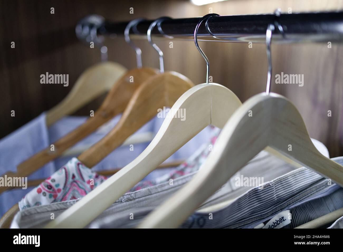Color clothes hang on clothing rack in a wooden cabinet with lighting ...