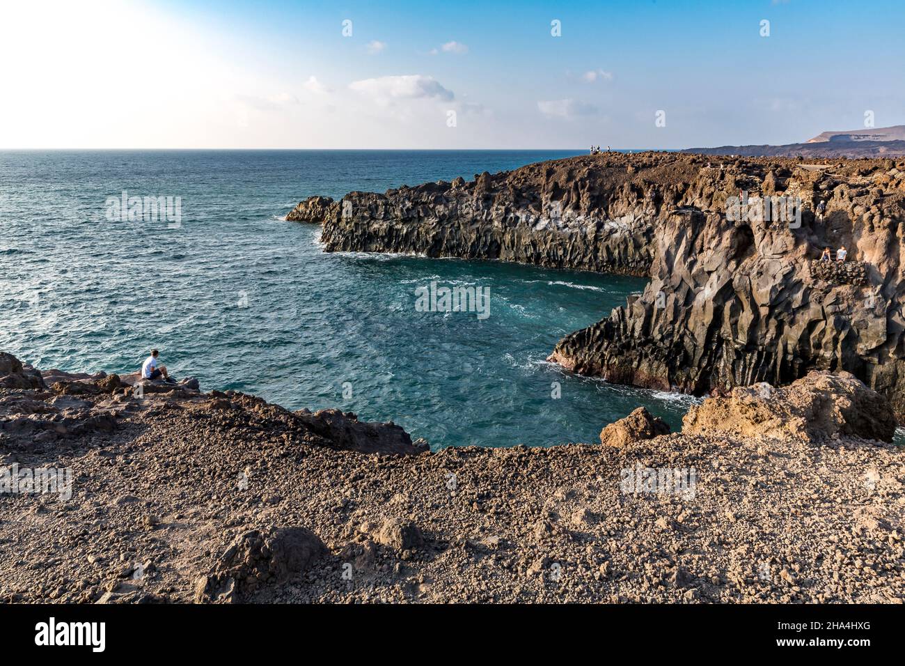 young man sits on a rock and enjoys the view,los hervideros lava rock ...
