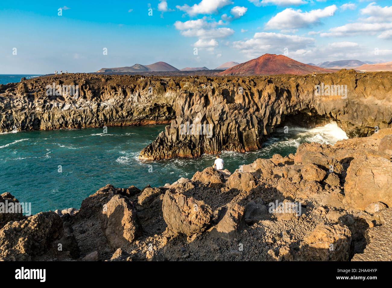 young man sits on a rock and enjoys the view,los hervideros lava rock ...