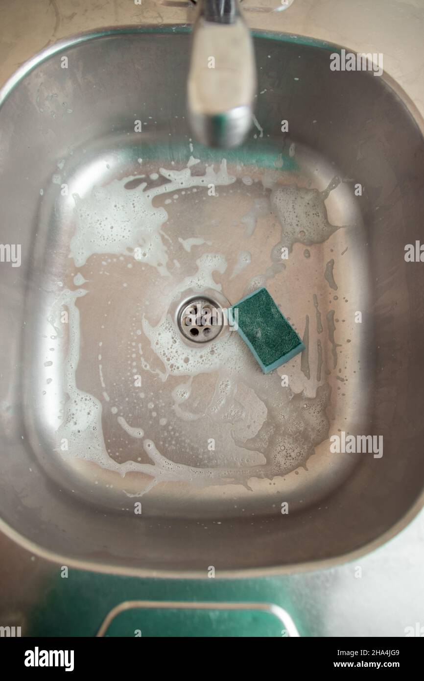 Cleaning and washing dirty kitchen sink with detergent and dish sponge ...