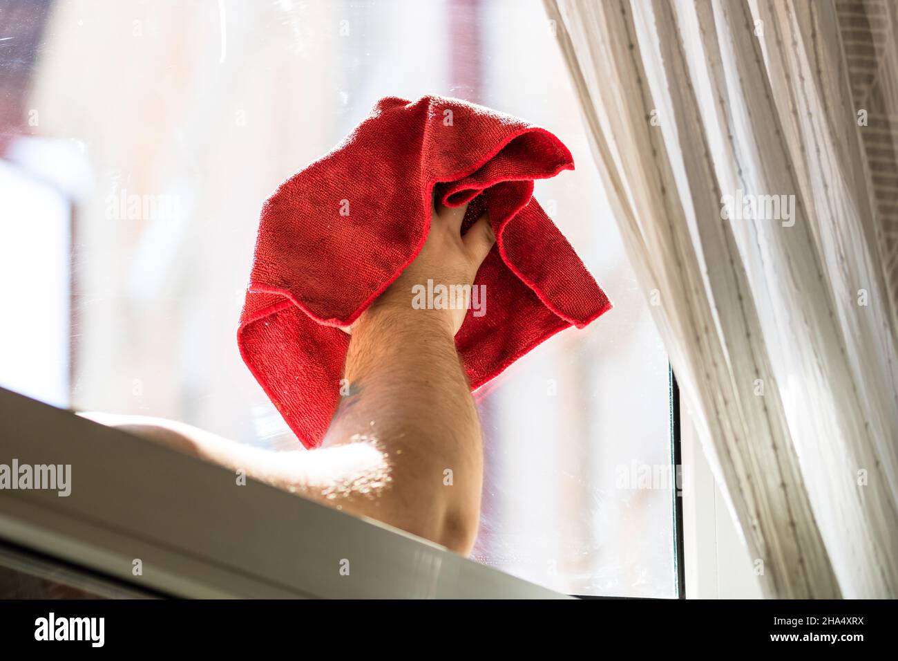 Man wiping window using red microfiber rug, cleaning services concept ...
