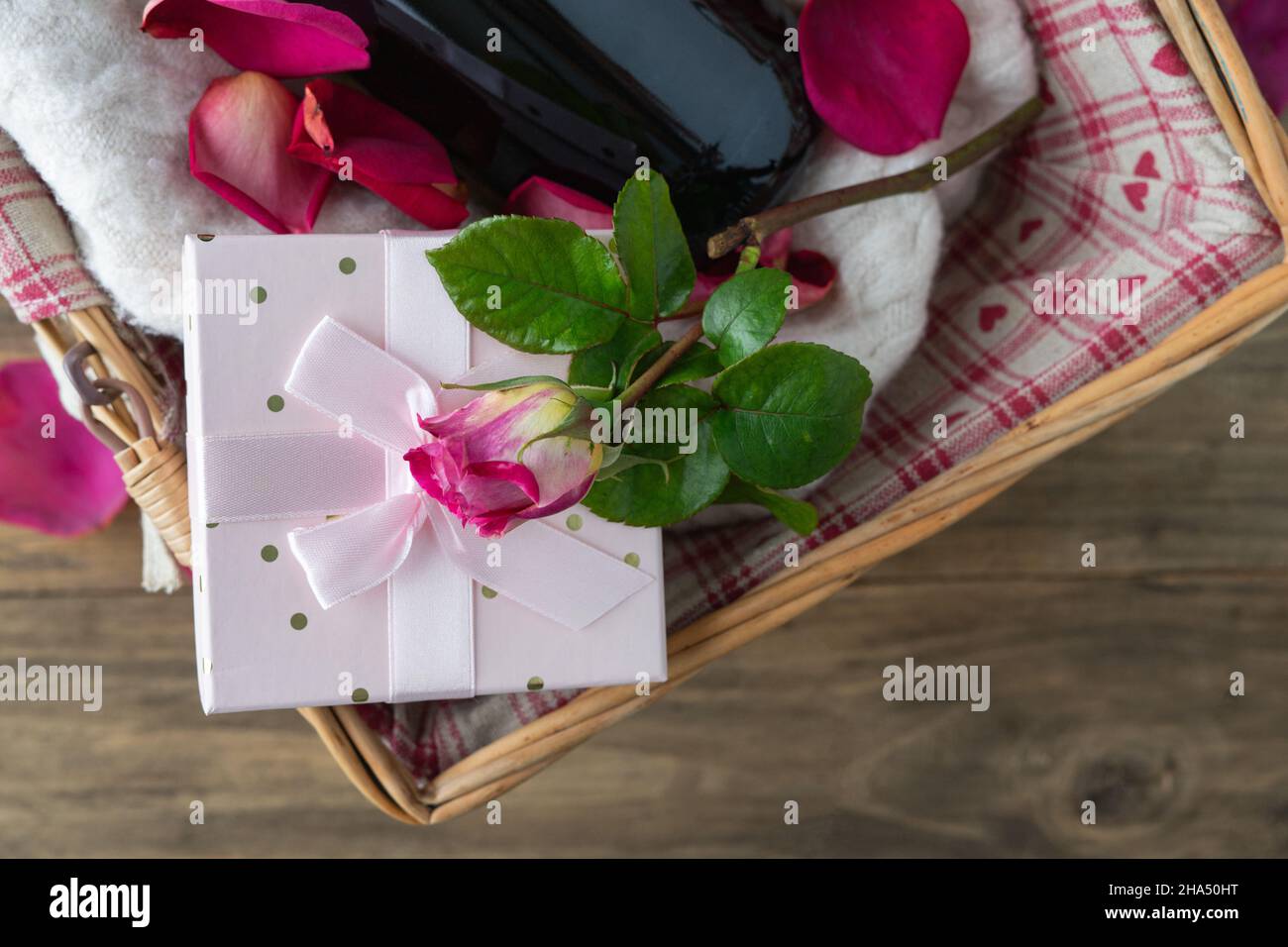 Valentine's Day. Gift basket with bottle, gift box and rose. Copy space ...